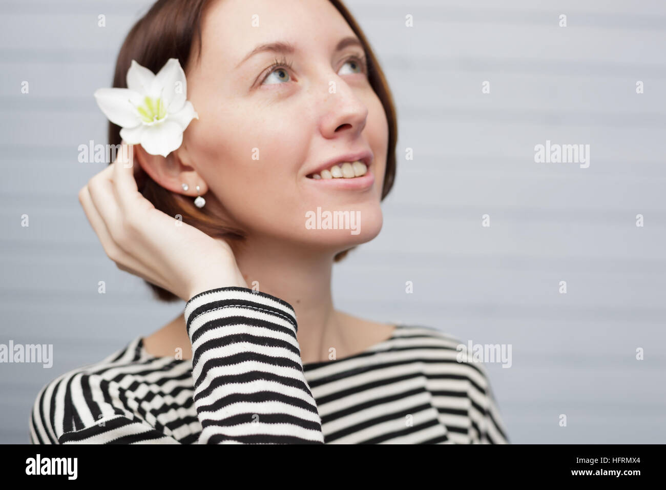 Loving girl looking up, pinning a flower to her ear Stock Photo - Alamy