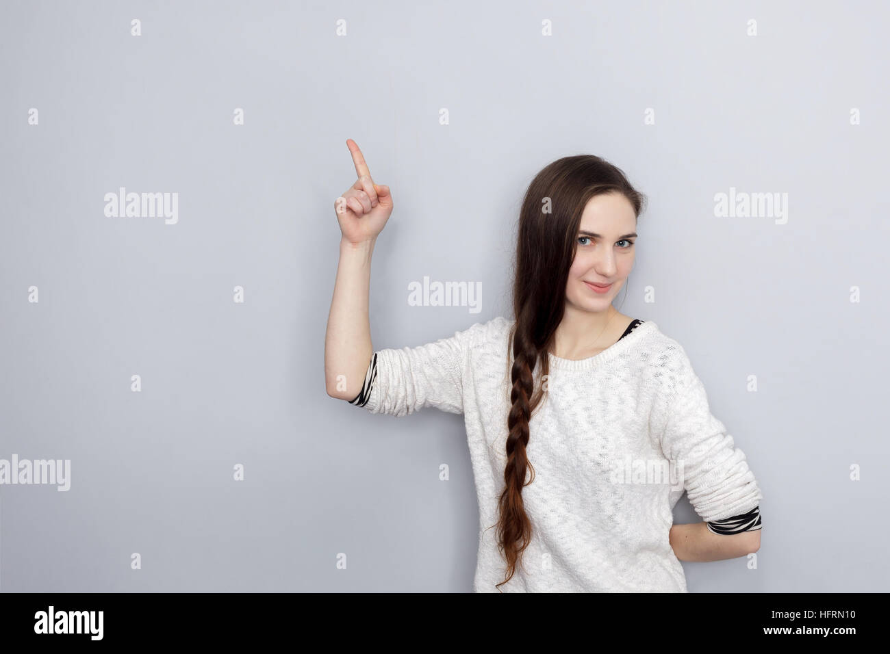 Girl with long hair shows index finger up, attracting attention Stock ...