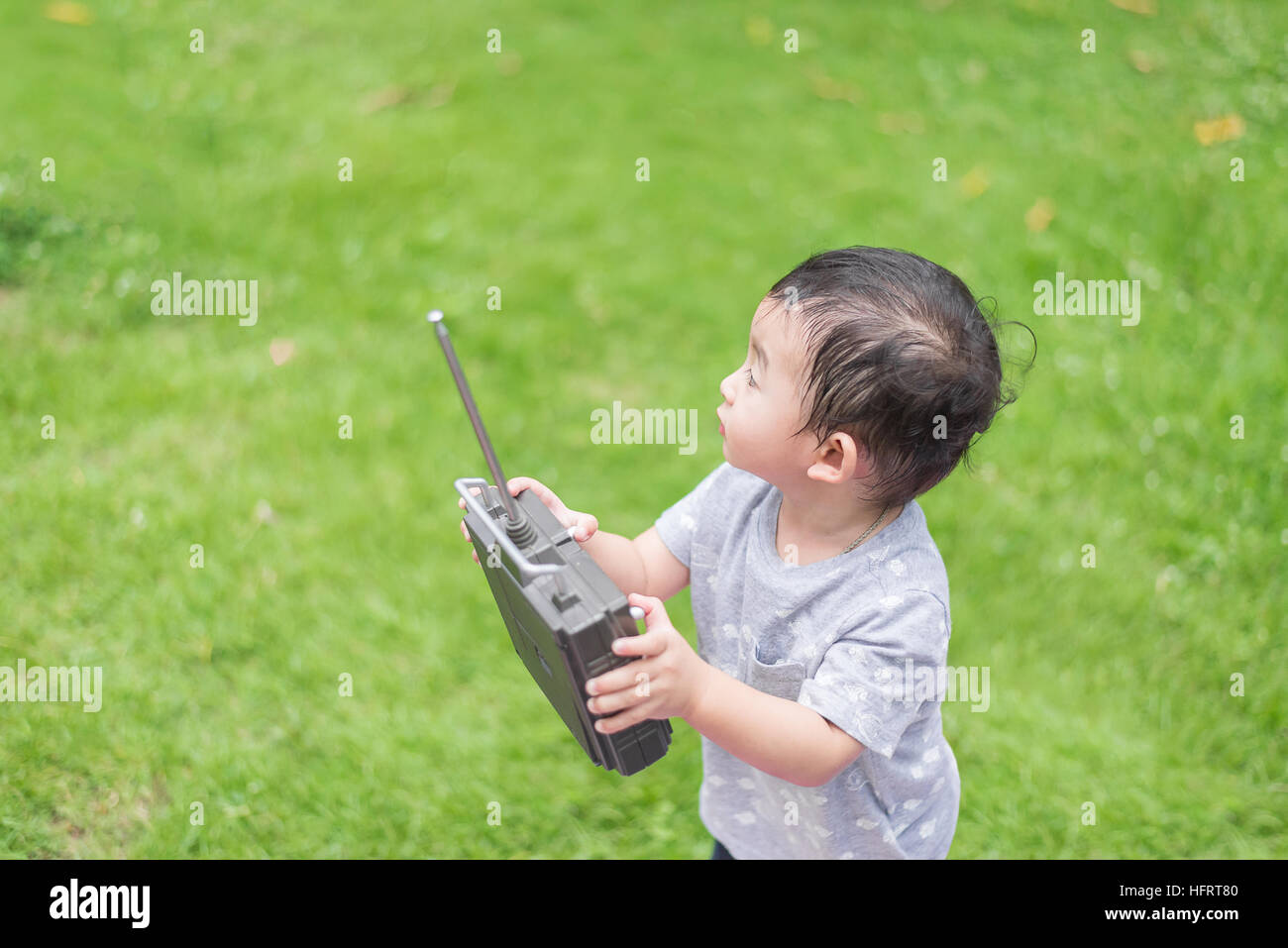 Little Asian kid holding a radio remote control (controlling handset ...