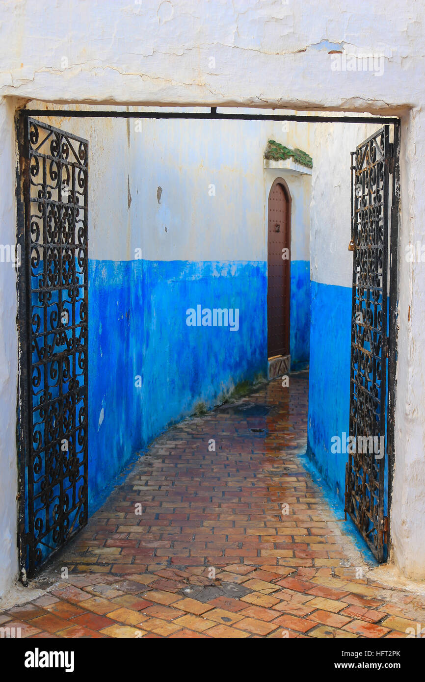Entrance to White and Blue painted narrow alleyway in a small town in ...