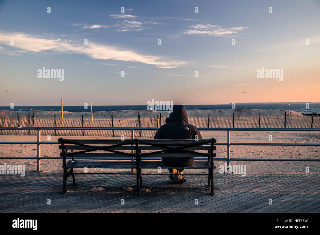 Woman sitting on the bench, overlooking the ocean at the boardwalk in ...