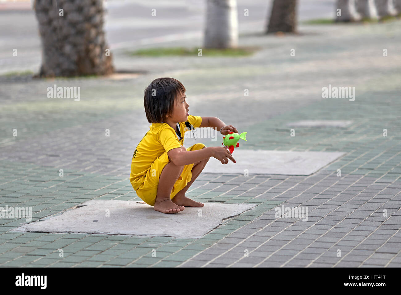 Child playing alone in a Thailand street. S. E. Asia Stock Photo - Alamy
