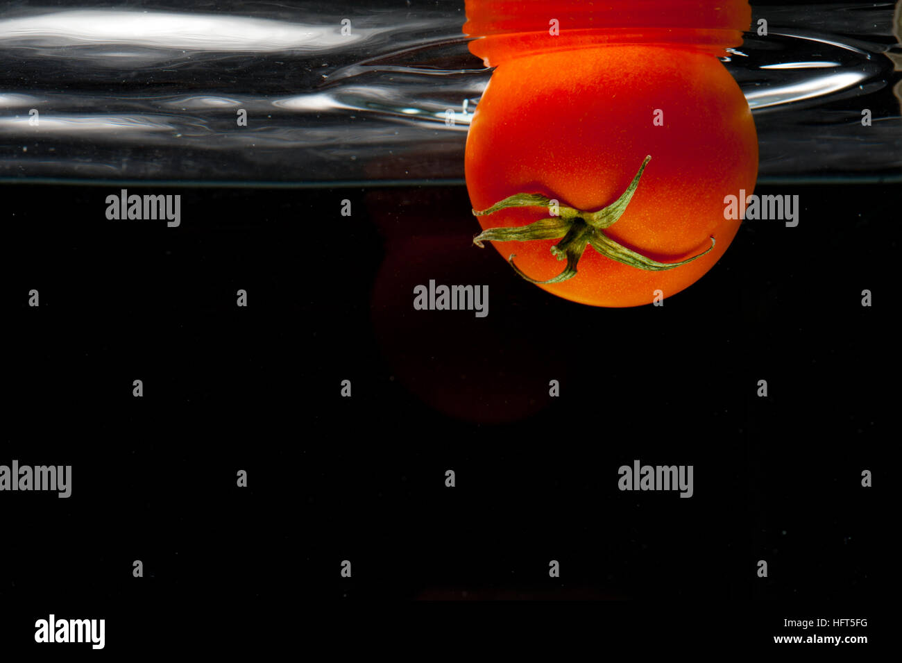 Tomato floating in the water on a black background Stock Photo - Alamy