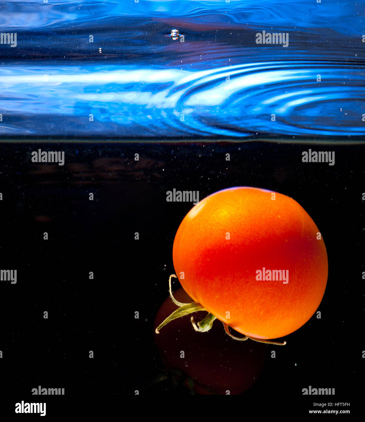Tomato floating in the water on a black background Stock Photo - Alamy