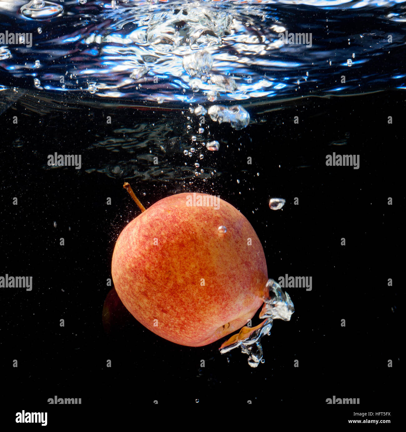 apple fell into the water by raising bubbles. On a black background ...