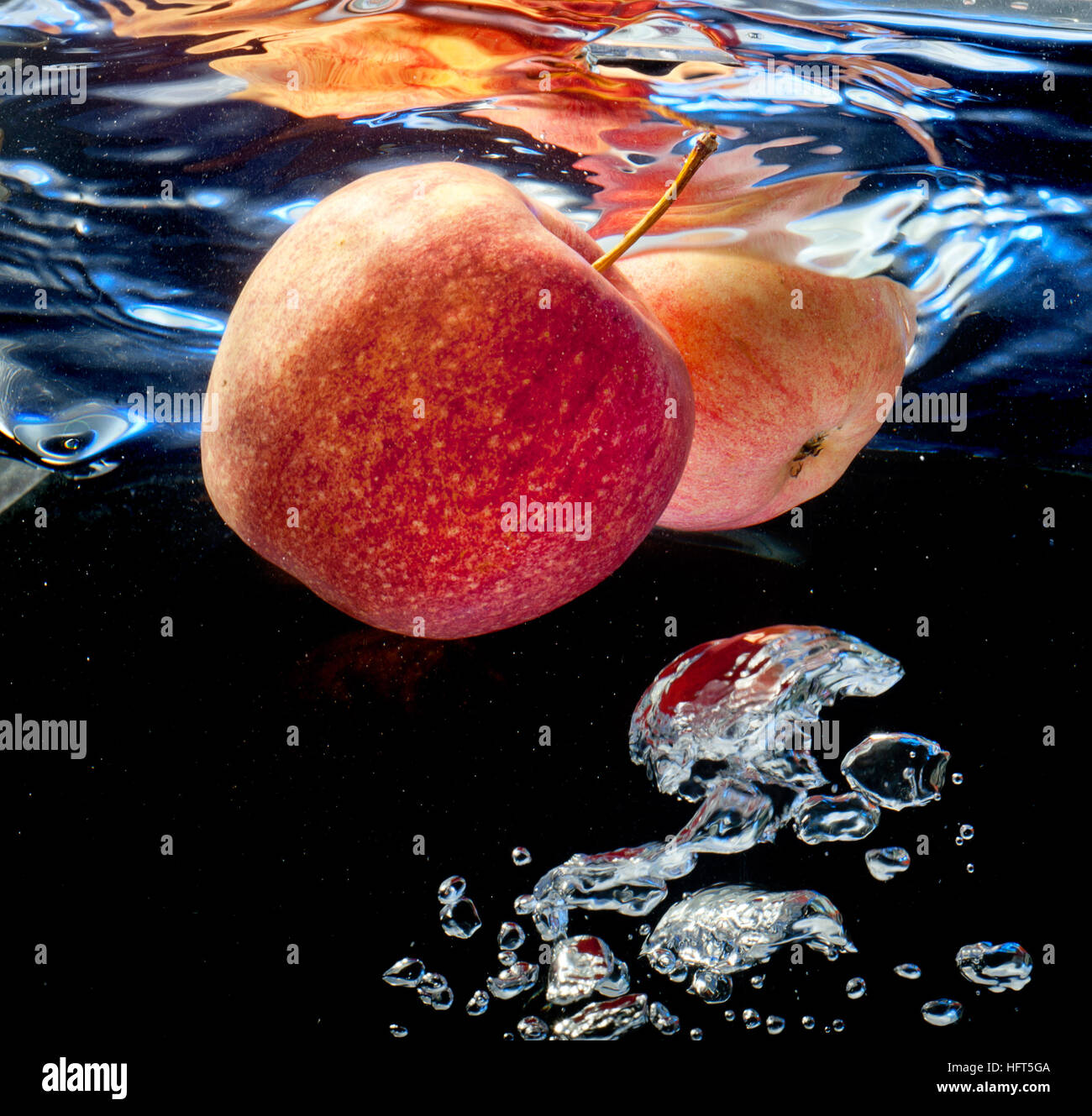 apple fell into the water by raising bubbles. On a black background ...