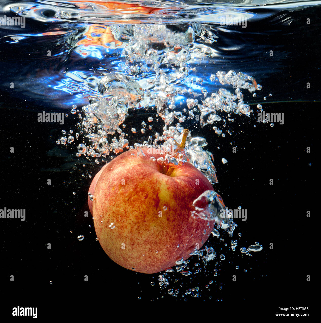 apple fell into the water by raising bubbles. On a black background ...