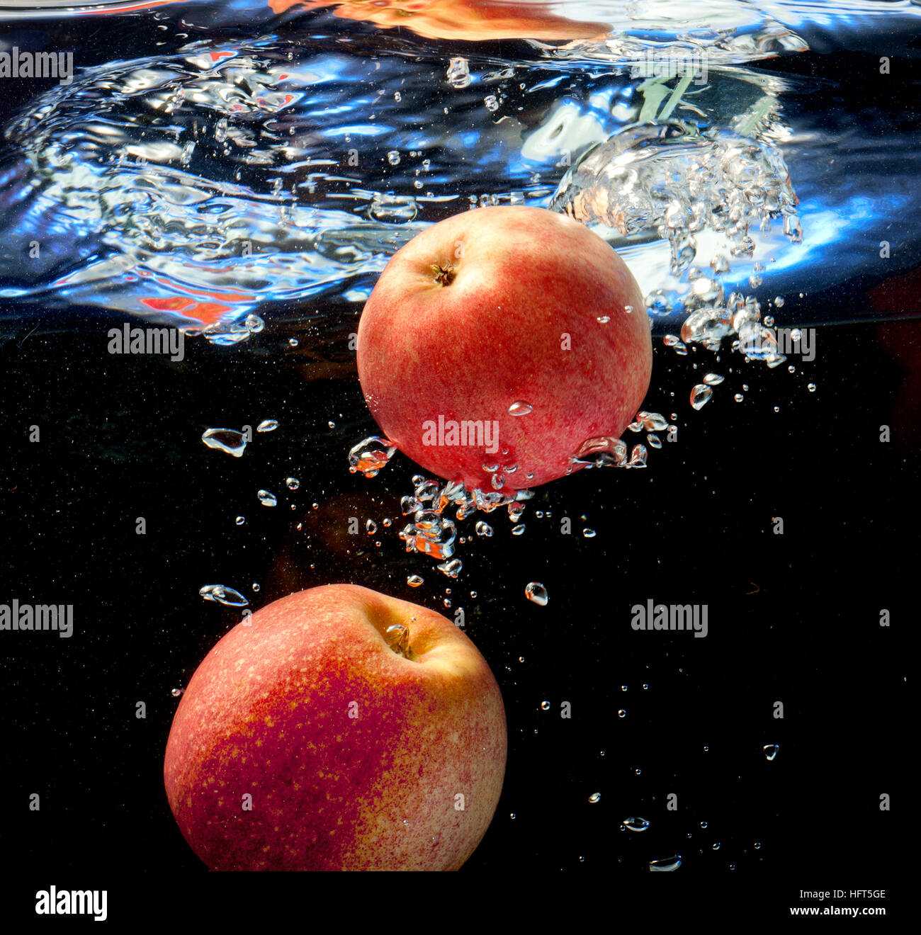 apple fell into the water by raising bubbles. On a black background ...