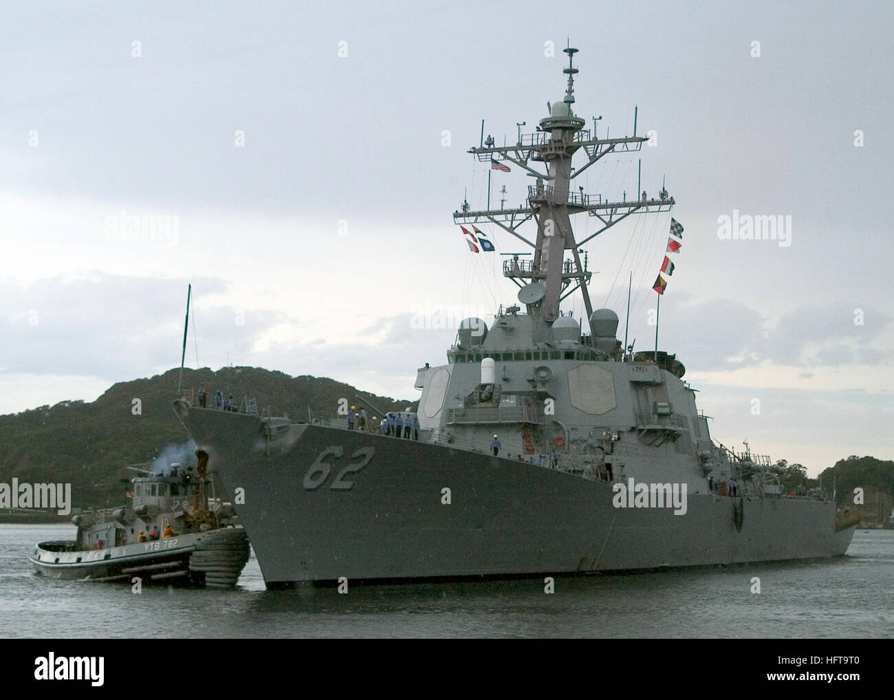 A large harbor tug maneuvers the guided-missile destroyer USS ...