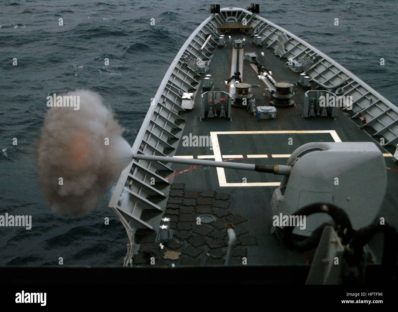 An Mk 45 Mod 4 gun fires from the bow of the guided-missile cruiser USS ...