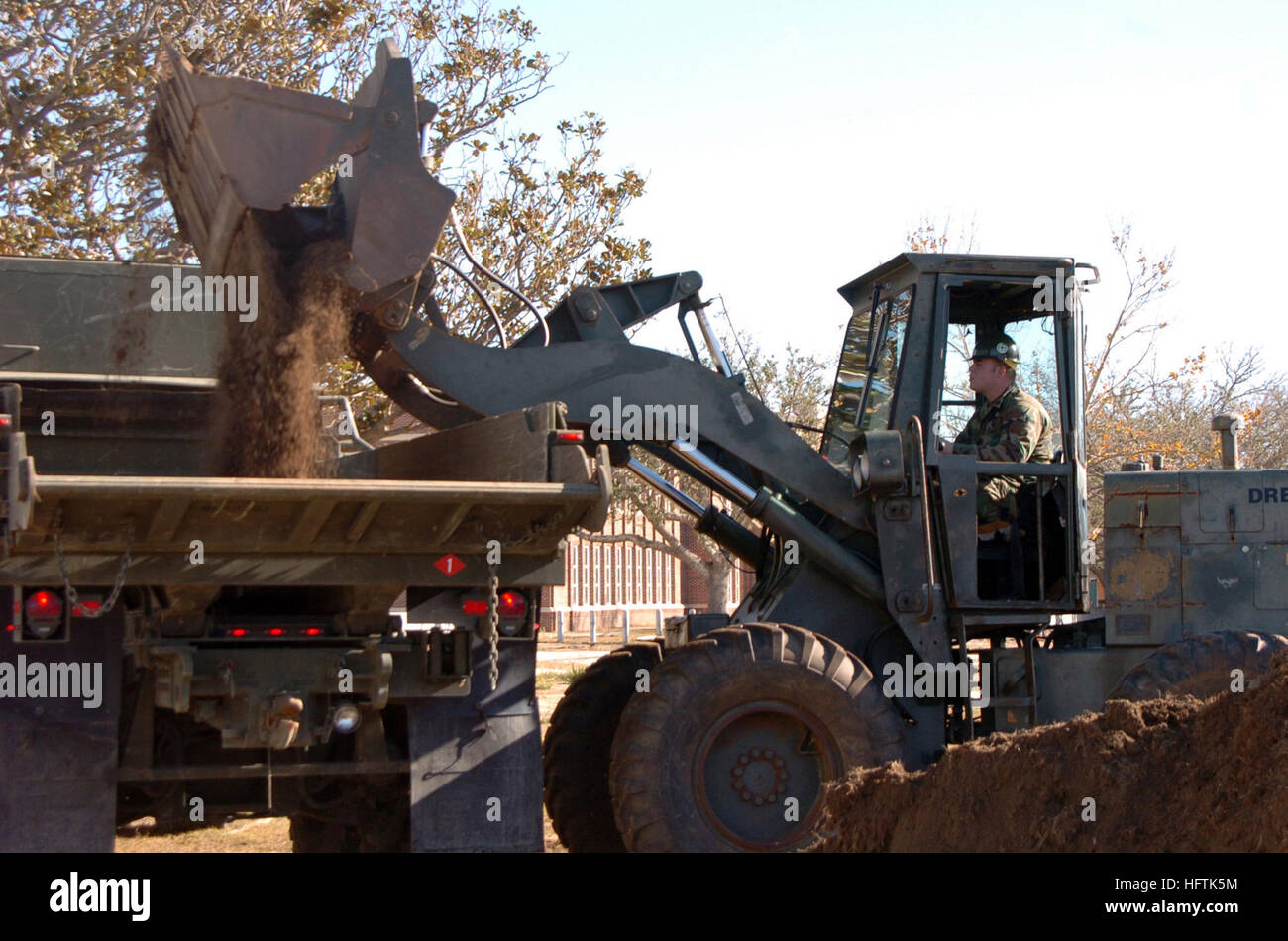 Naval Mobile Construction Battalion 7 uses a front-end loader to remove ...