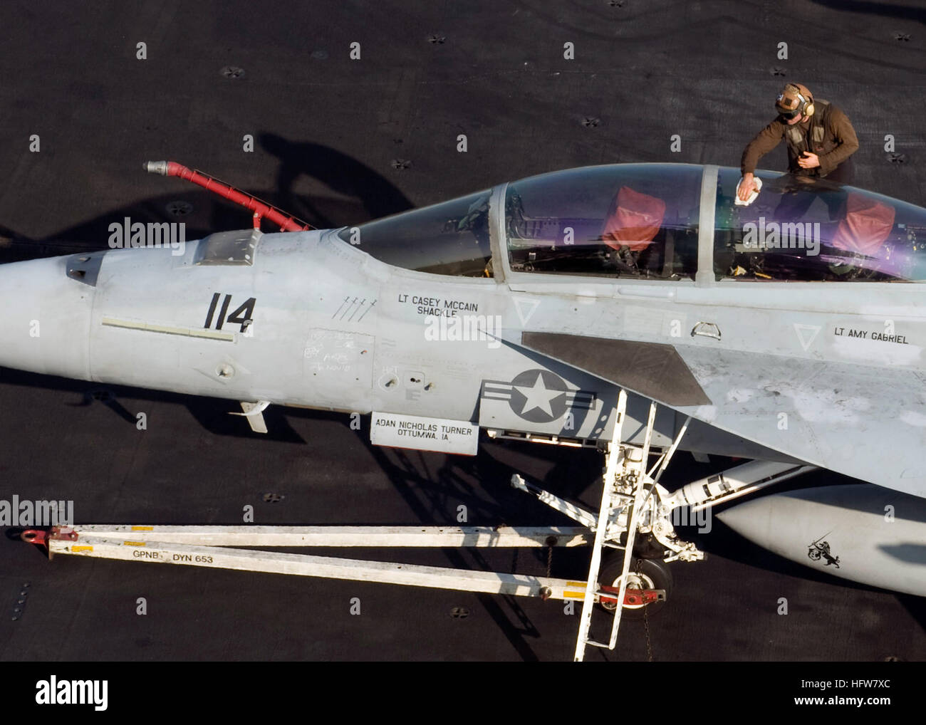 A plane captain cleans the canopy of an F/A-18 aboard the aircraft ...