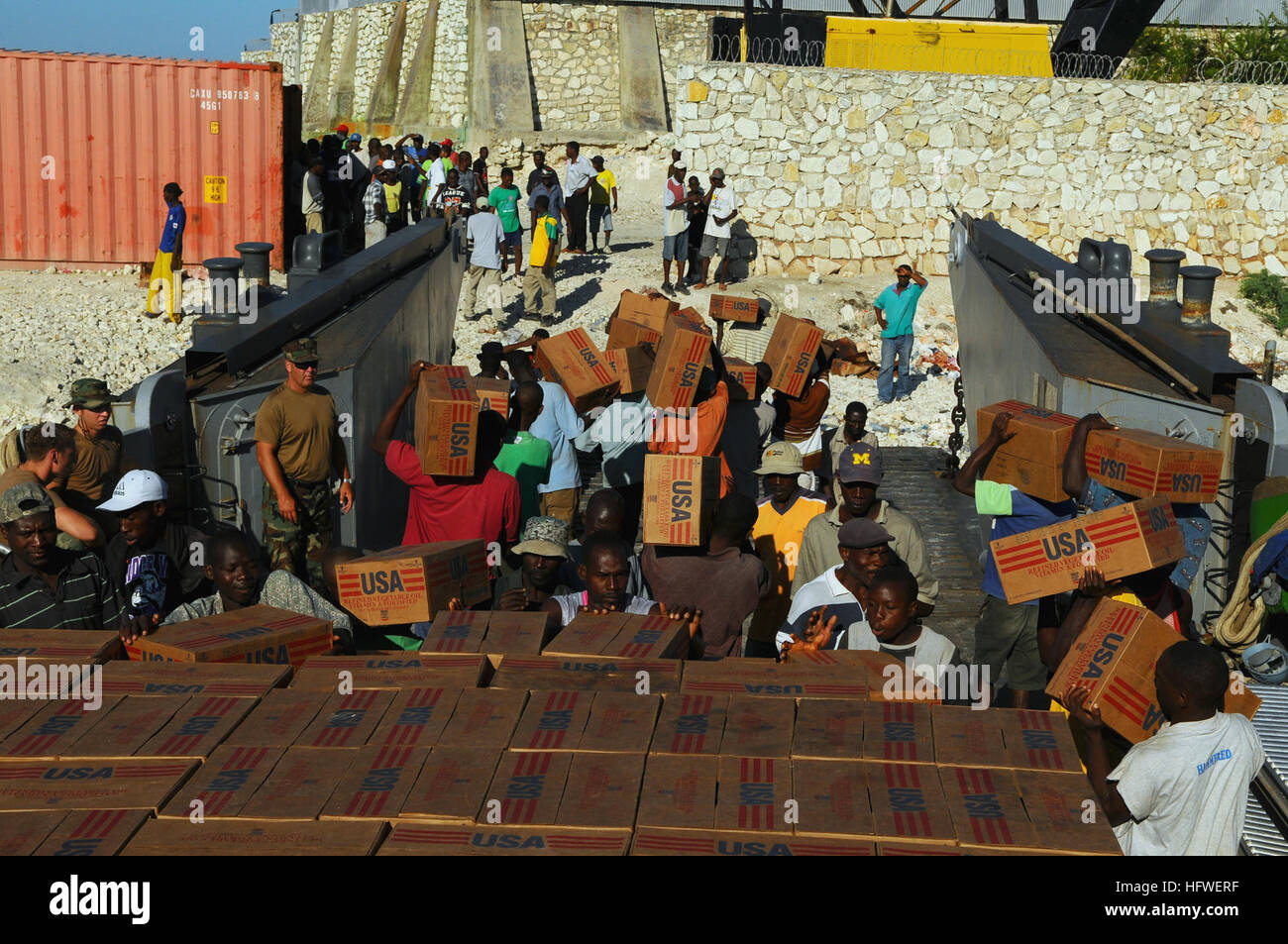 Haitian civilians unload relief supplies from landing craft utility of ...