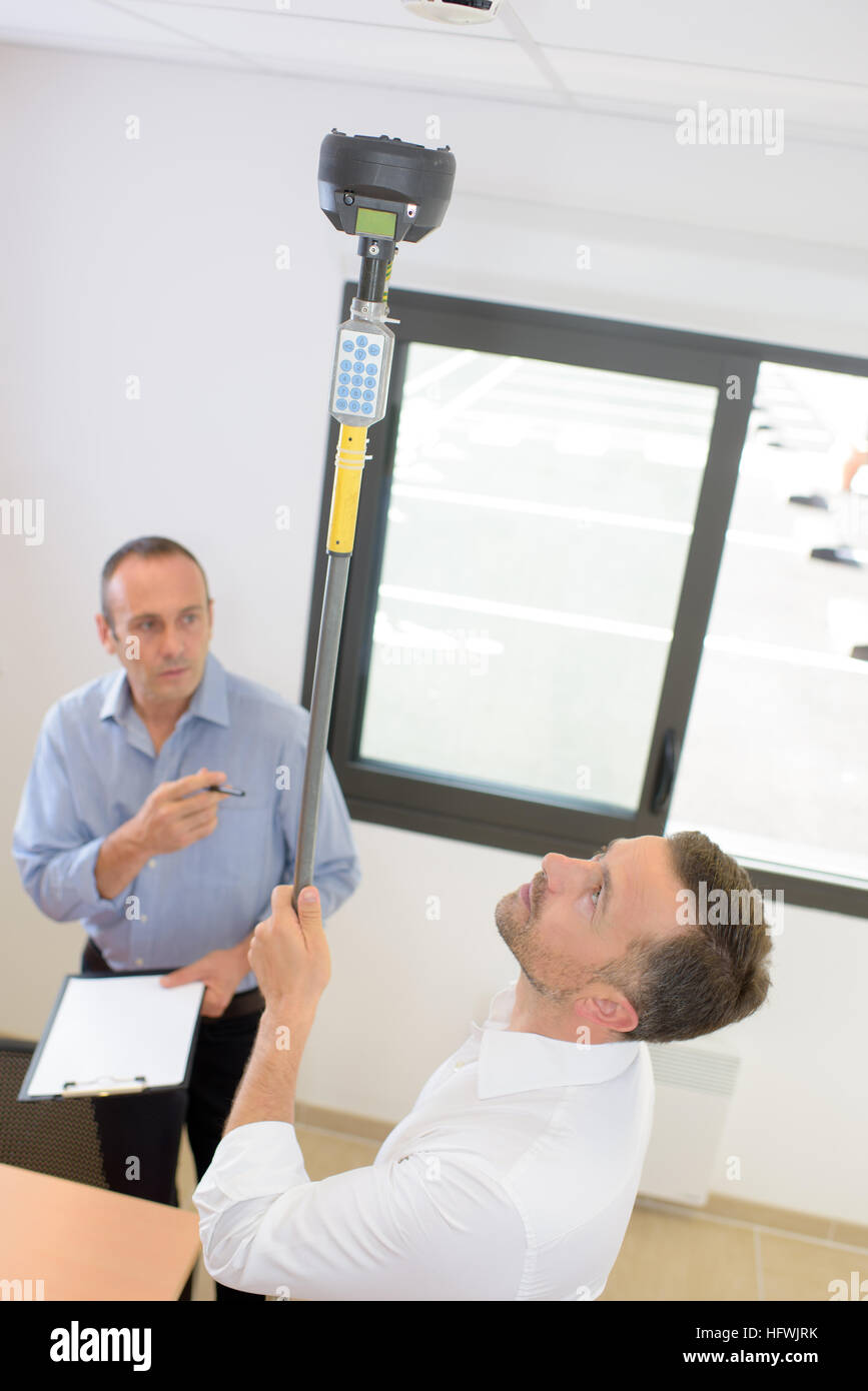 Man testing smoke detector with extendable device Stock Photo - Alamy