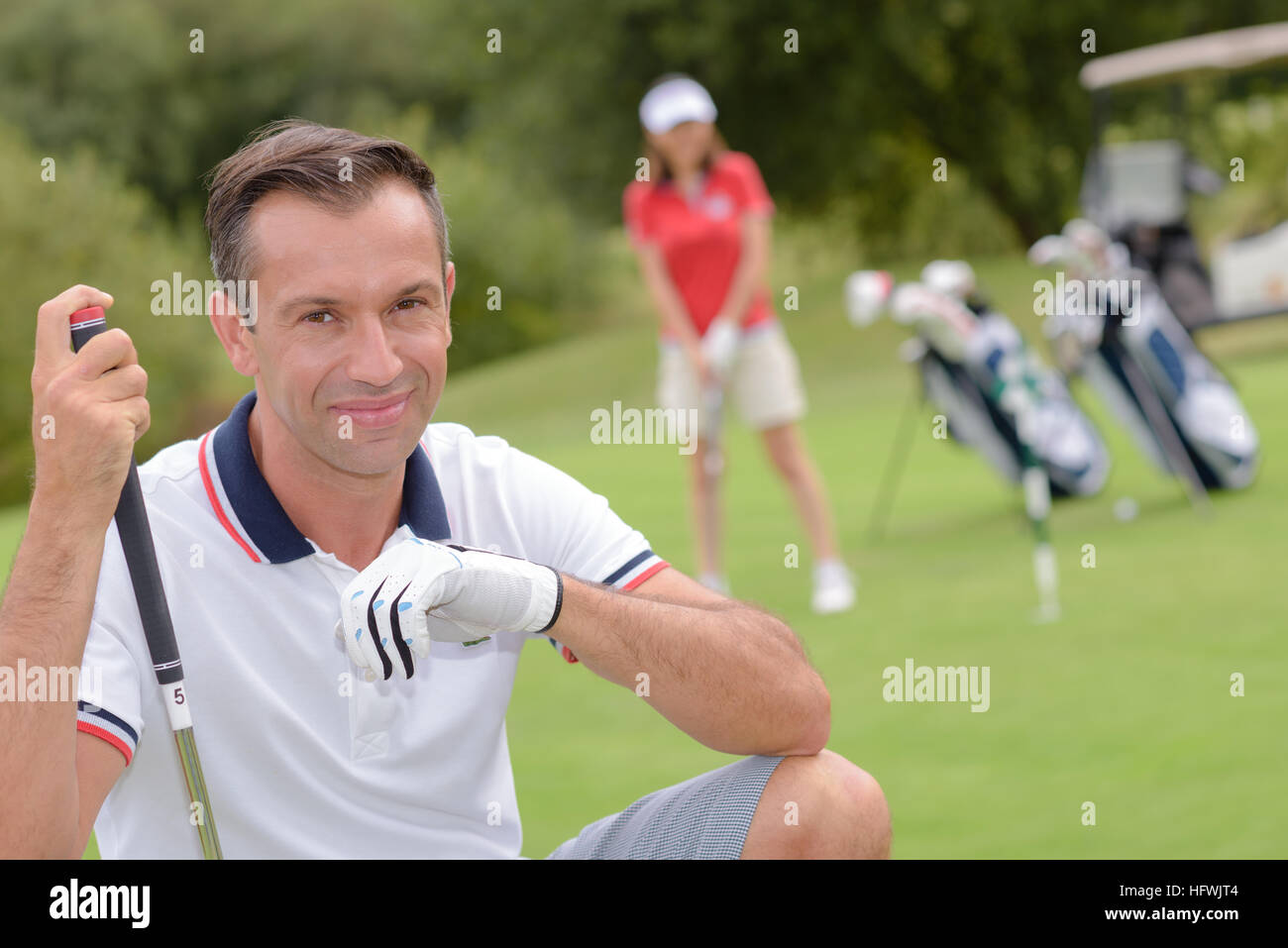 Portrait of male golfer, wife playing in background Stock Photo - Alamy