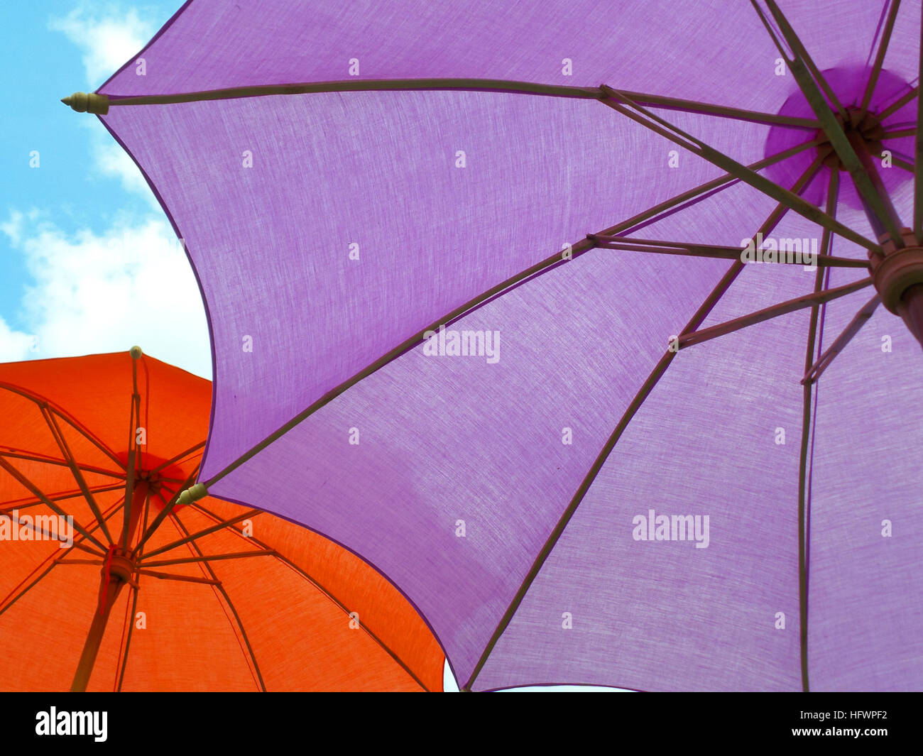 Two vivid colored parasols, one purple and one red against the blue sky ...