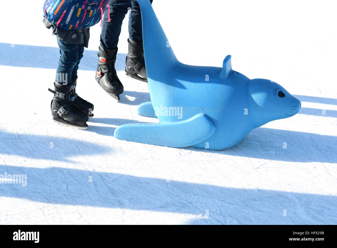 Family fun on outdoor ice rink, kid learning to skate with plastic seal ...