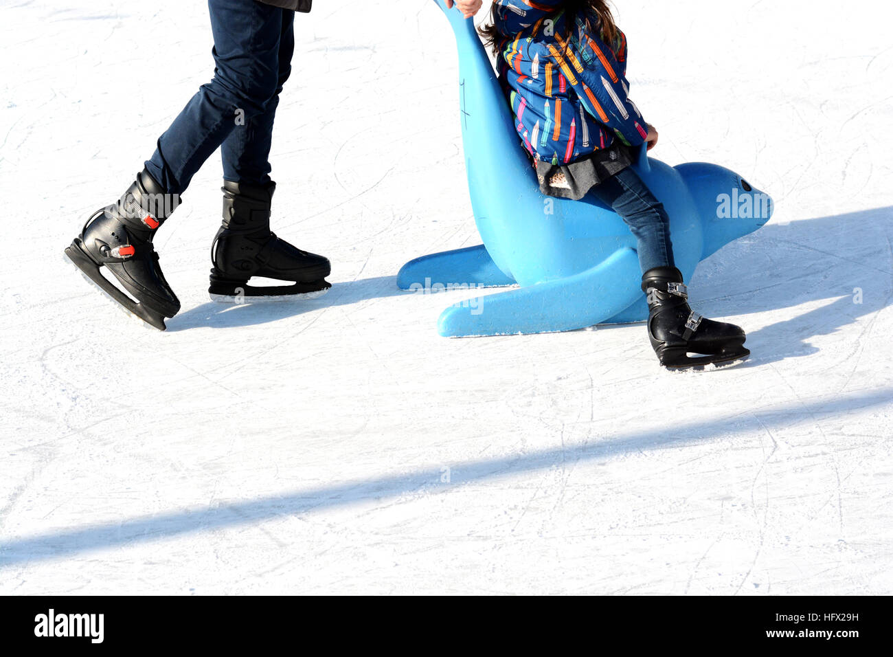 Family fun on outdoor ice rink, kid learning to skate with plastic seal ...