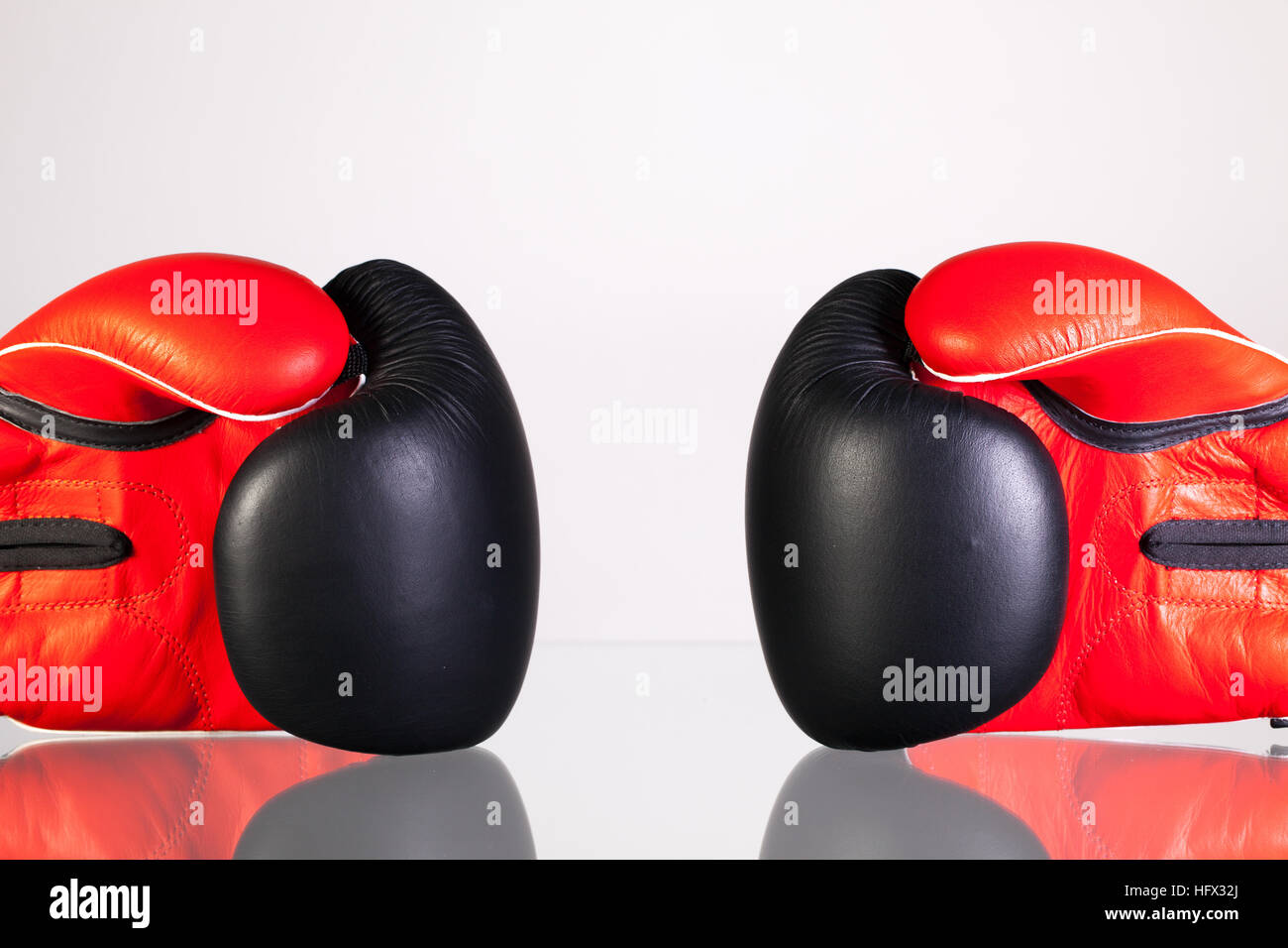 Red and black boxing gloves on a glass table isolated on white ...