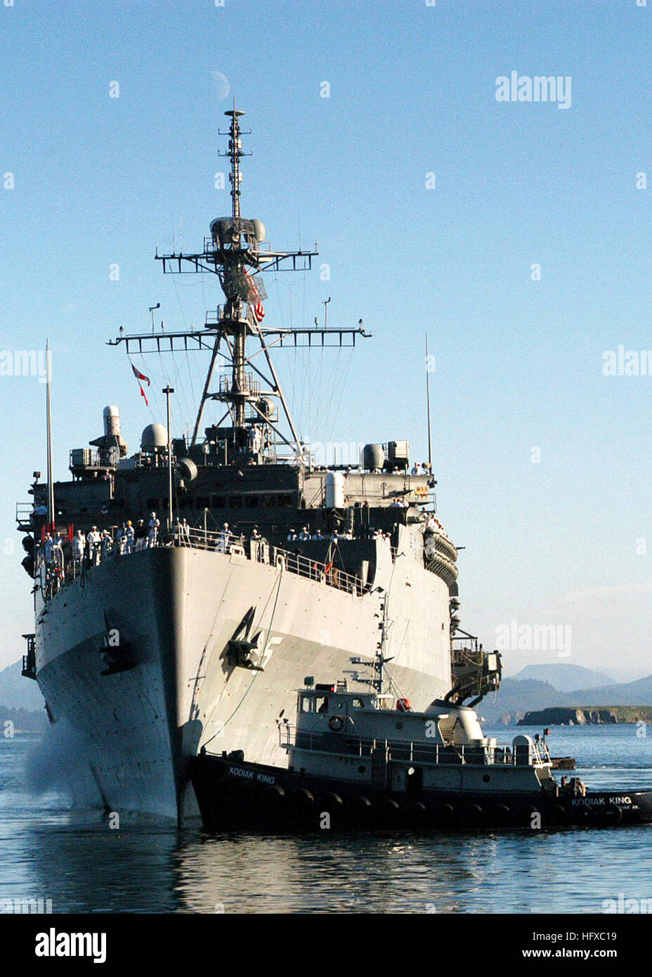 Amphibious transport dock USS Ogden (LPD 5) is assisted by a harbor tug ...