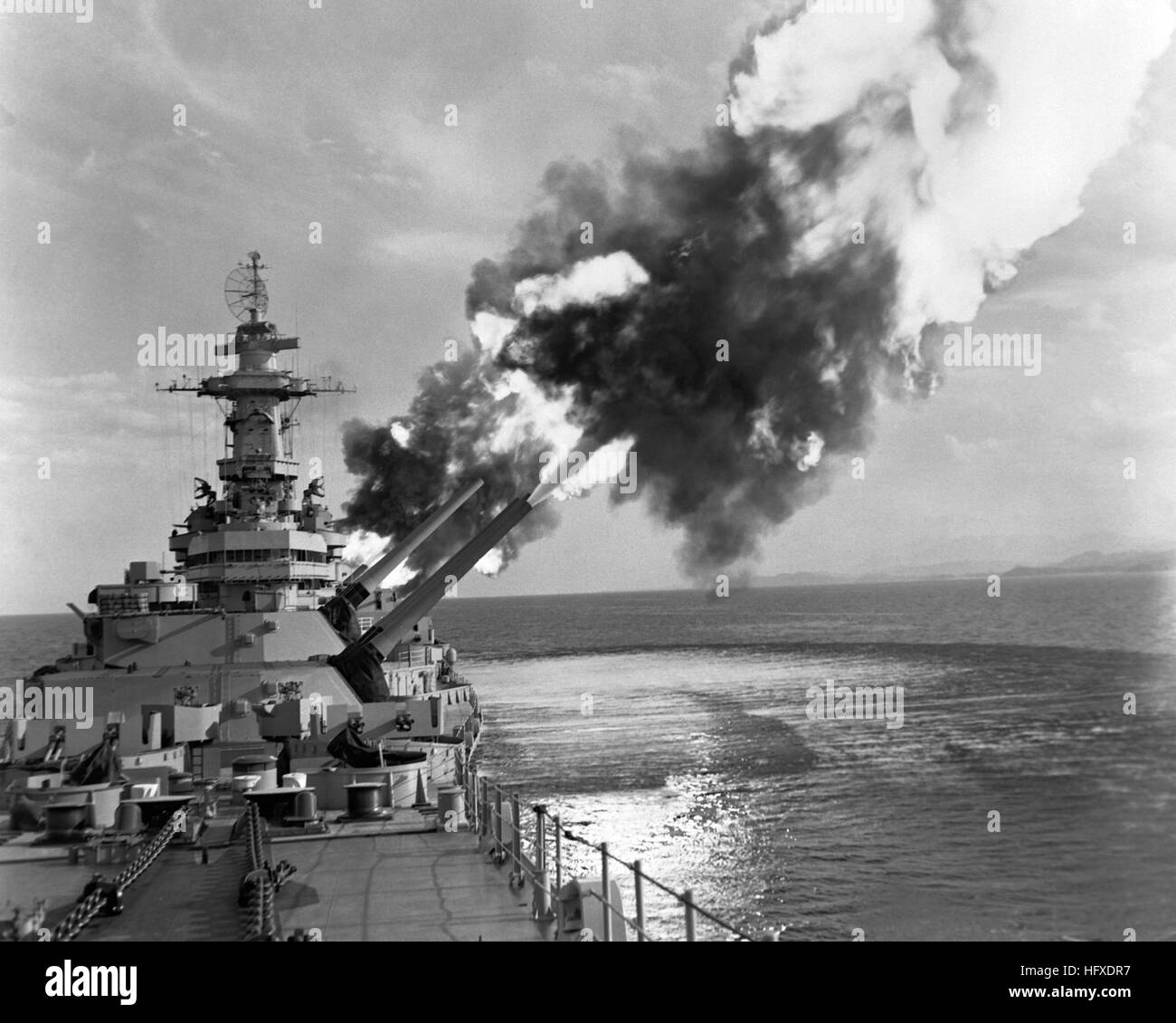 USS New Jersey (BB-62) fires a six-gun salvo of 16-inch shells toward ...