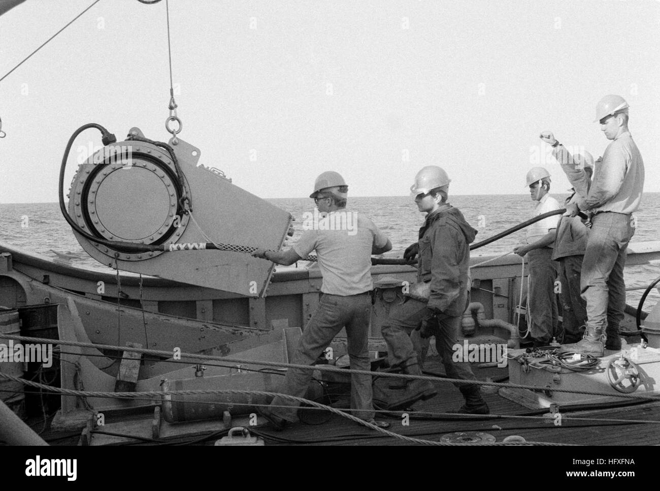 Crew members lower an acoustical device into the water from the ocean ...