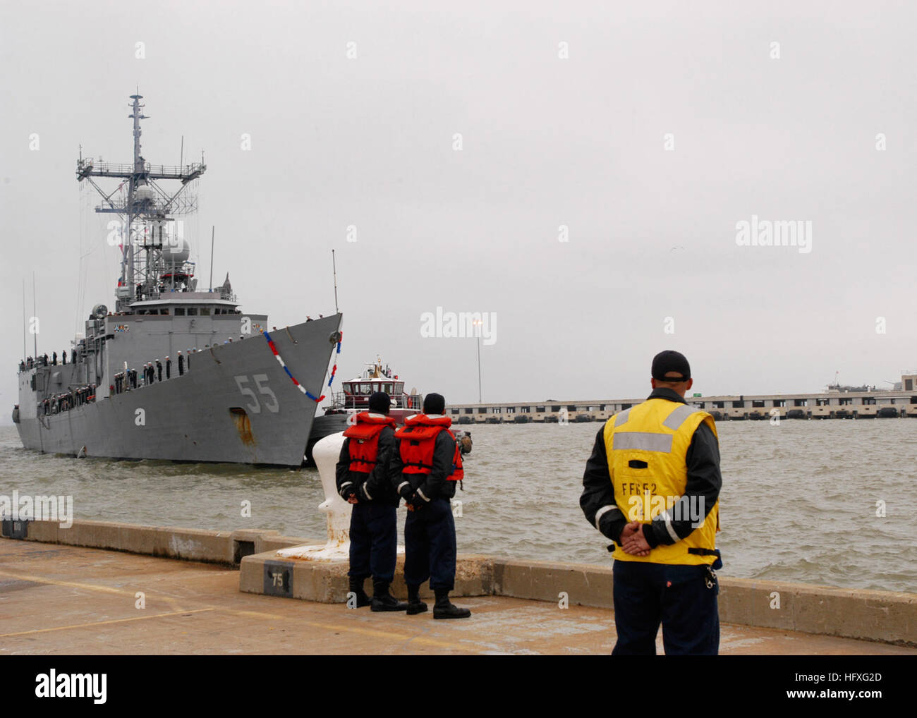 Line handlers stand by for the arrival of the guided missile frigate ...
