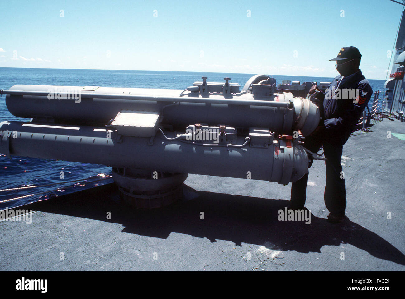 A crewman closes the breech of a Mark 32 12.75-inch torpedo launcher ...