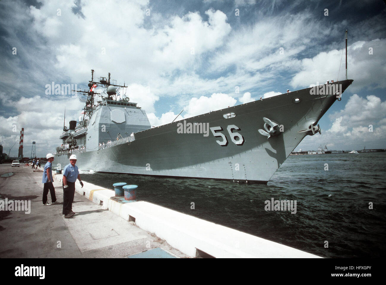 Dock workers stand by to help moor the guided missile cruiser USS SAN ...