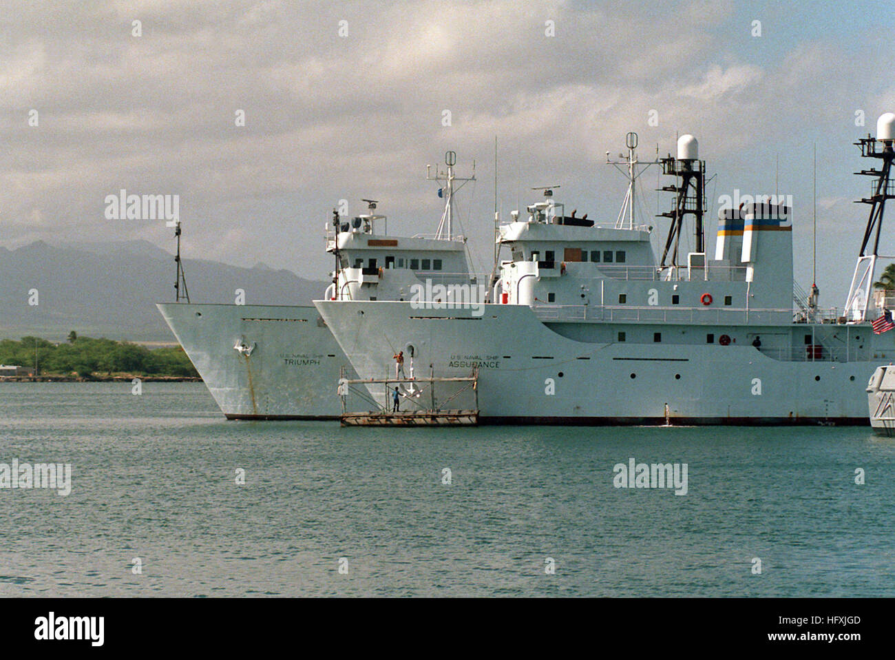 Crew members paint the anchor of the ocean surveillance ship USNS ...