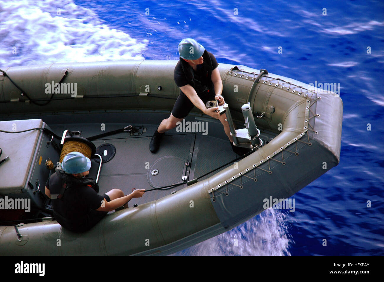 Rescue swimmers help steer a rigid hull inflatable boat after being ...