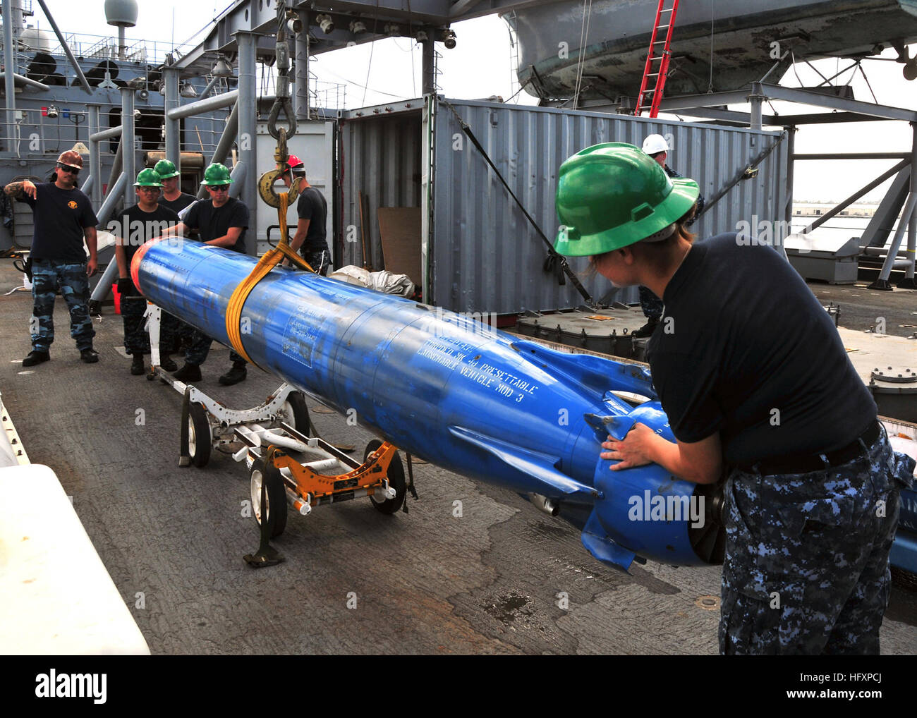 Sailors and civilian mariners aboard USS Frank Cable (AS 40) lower a ...