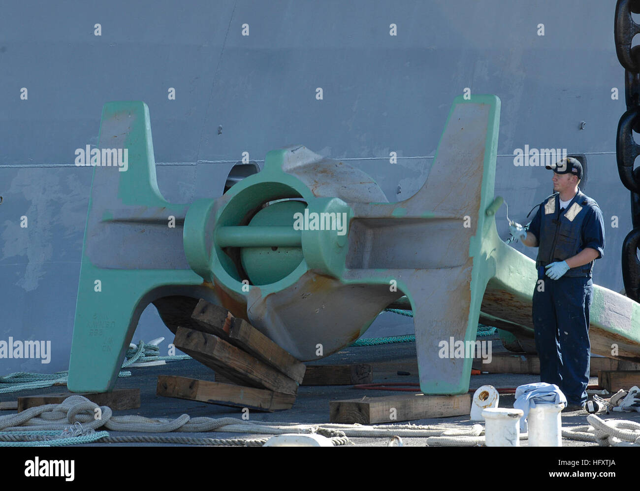 A Boatswain's Mate applies primer to the 30-ton portside anchor of ...