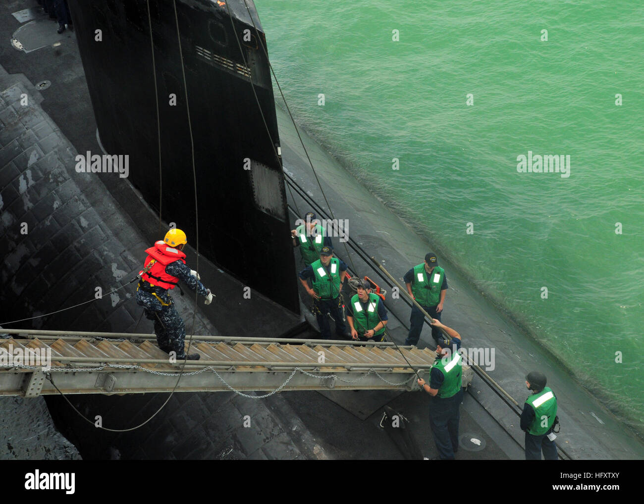 Sailors aboard submarine tender USS Frank Cable (AS 40) assist Los ...