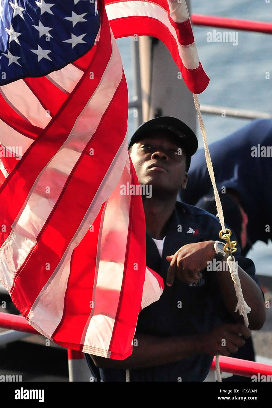 Quartermaster 2nd Class raises the American flag aboard amphibious dock ...