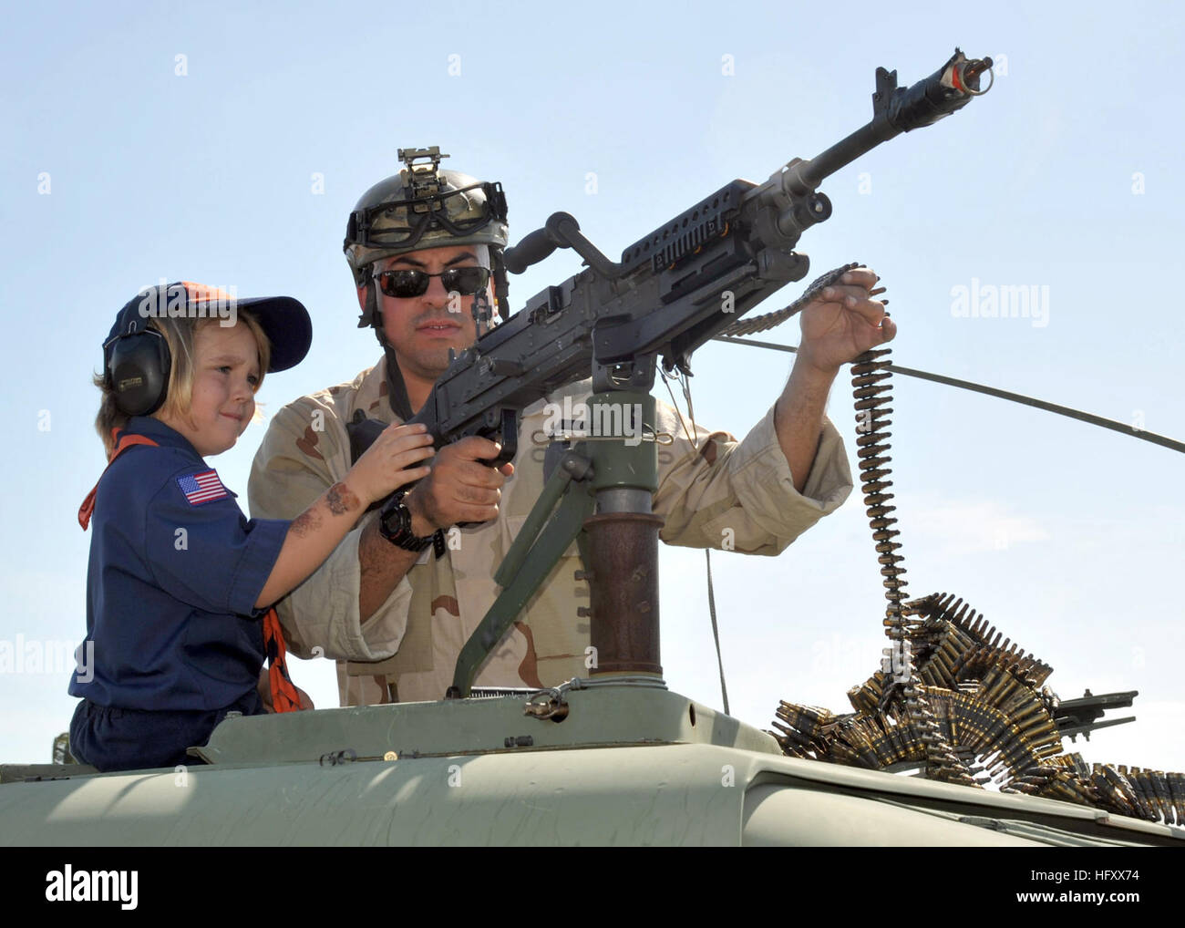 A Navy SEAL demonstrates an M240 machine gun to a child during the ...