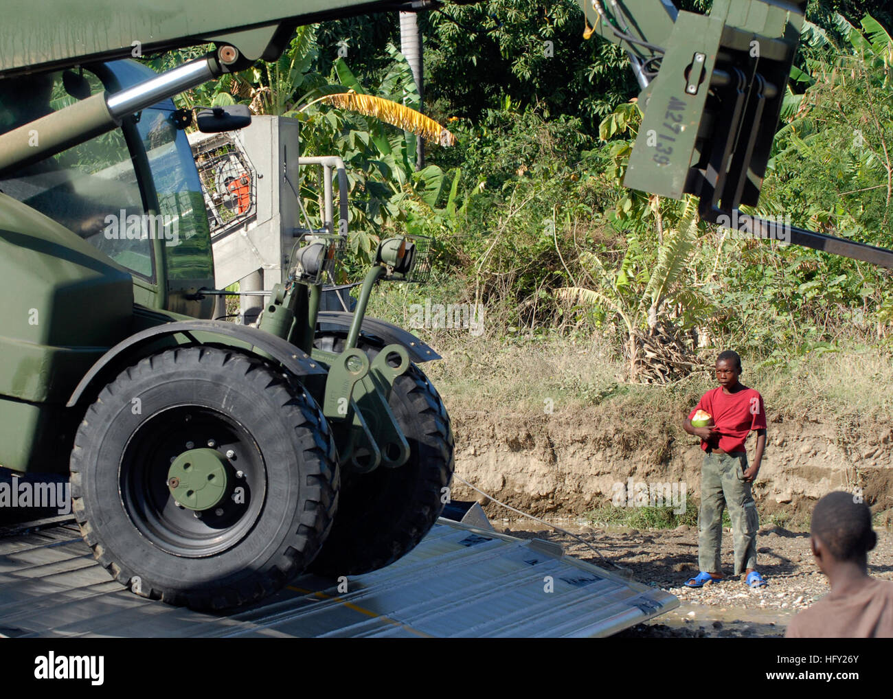 A Haitian boy looks on as a Seabee drives a forklift off an air ...