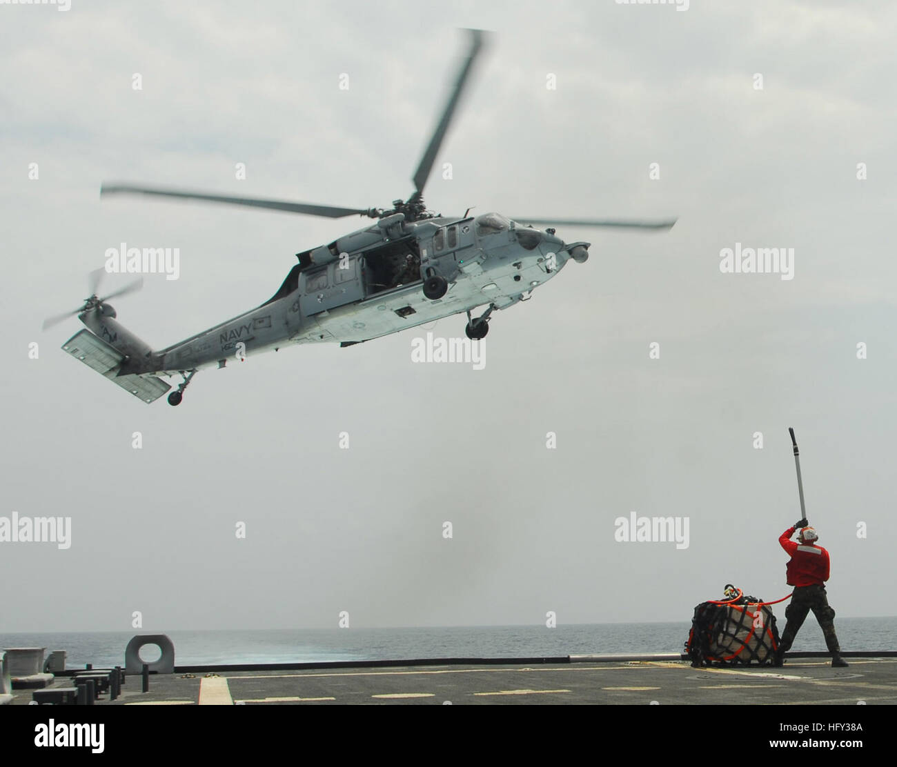 An Aviation Ordnanceman signals an MH-60S Sea Hawk helicopter to ...