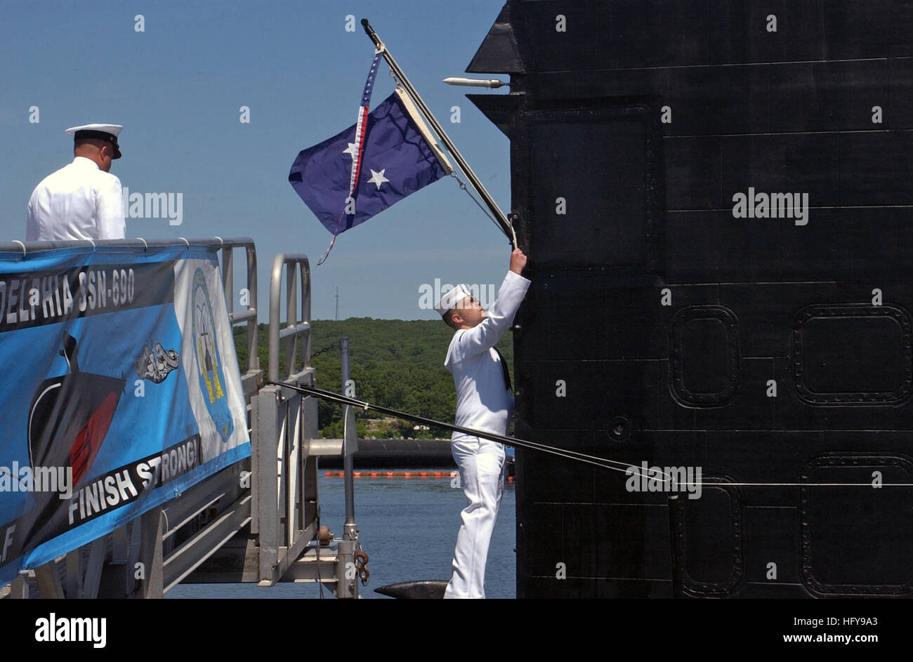 Petty Officer 1st Class Nicholas Harr lowers the commissioning pennant ...