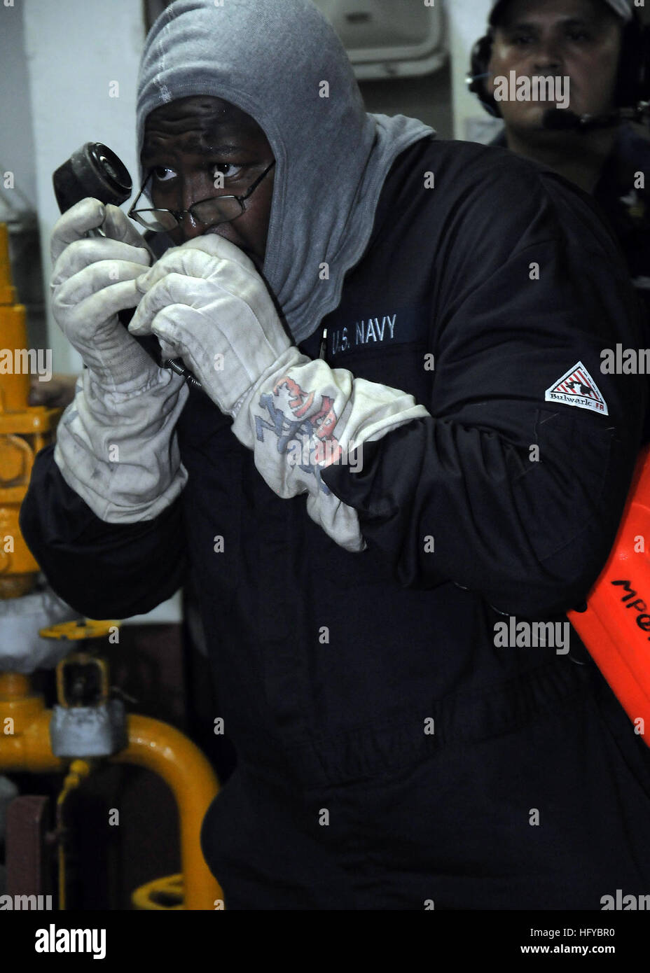 Aft machinery room phone talker aboard USS Bataan reports progress of damage control hose teams ...