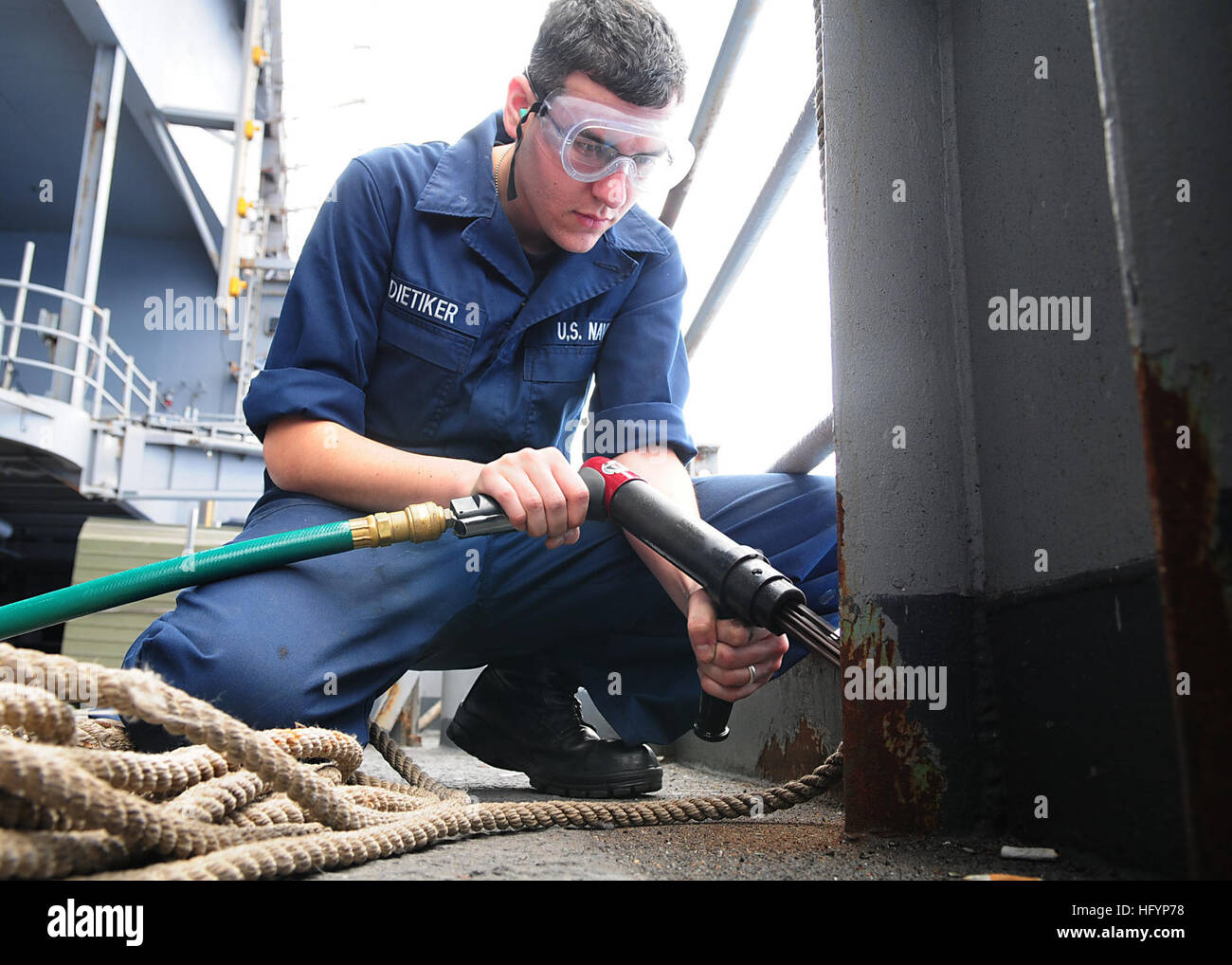 A Seaman Recruit removes rust from the fantail of the aircraft carrier ...