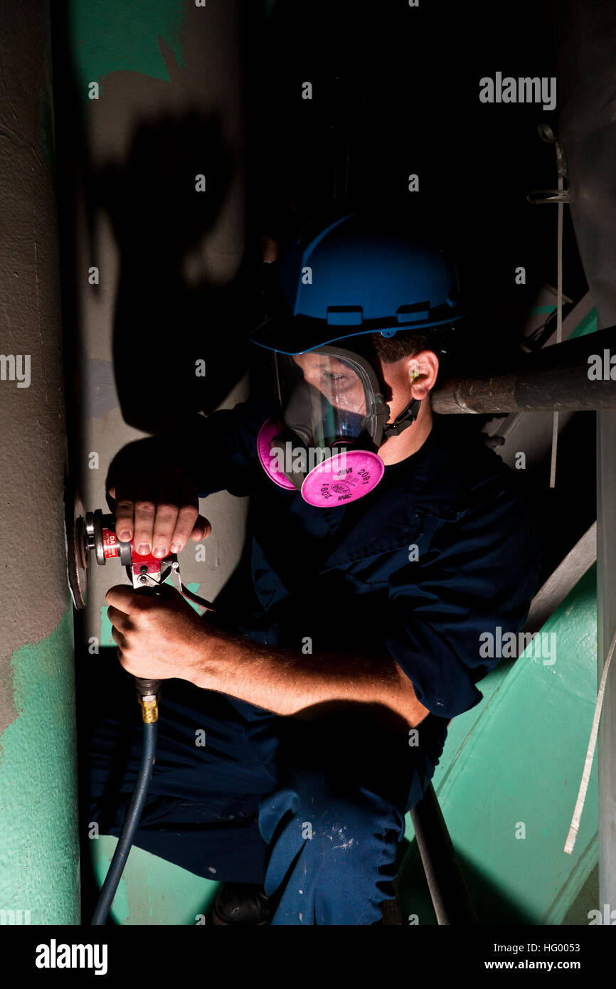 Boatswain's Mate 1st Class uses a power grinder inside the ...