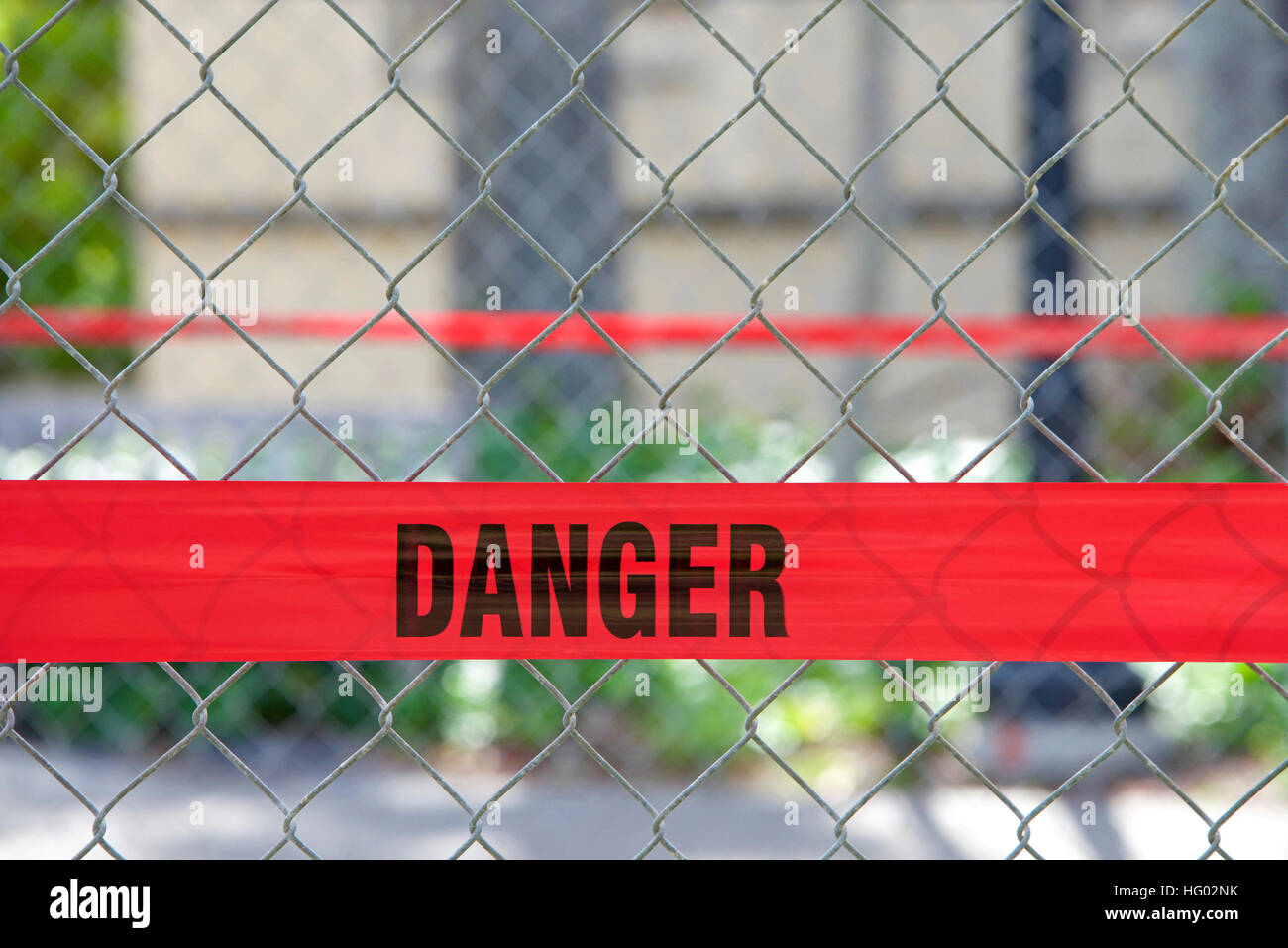 Red reflective danger barrier tape across a chain link fence to keep ...