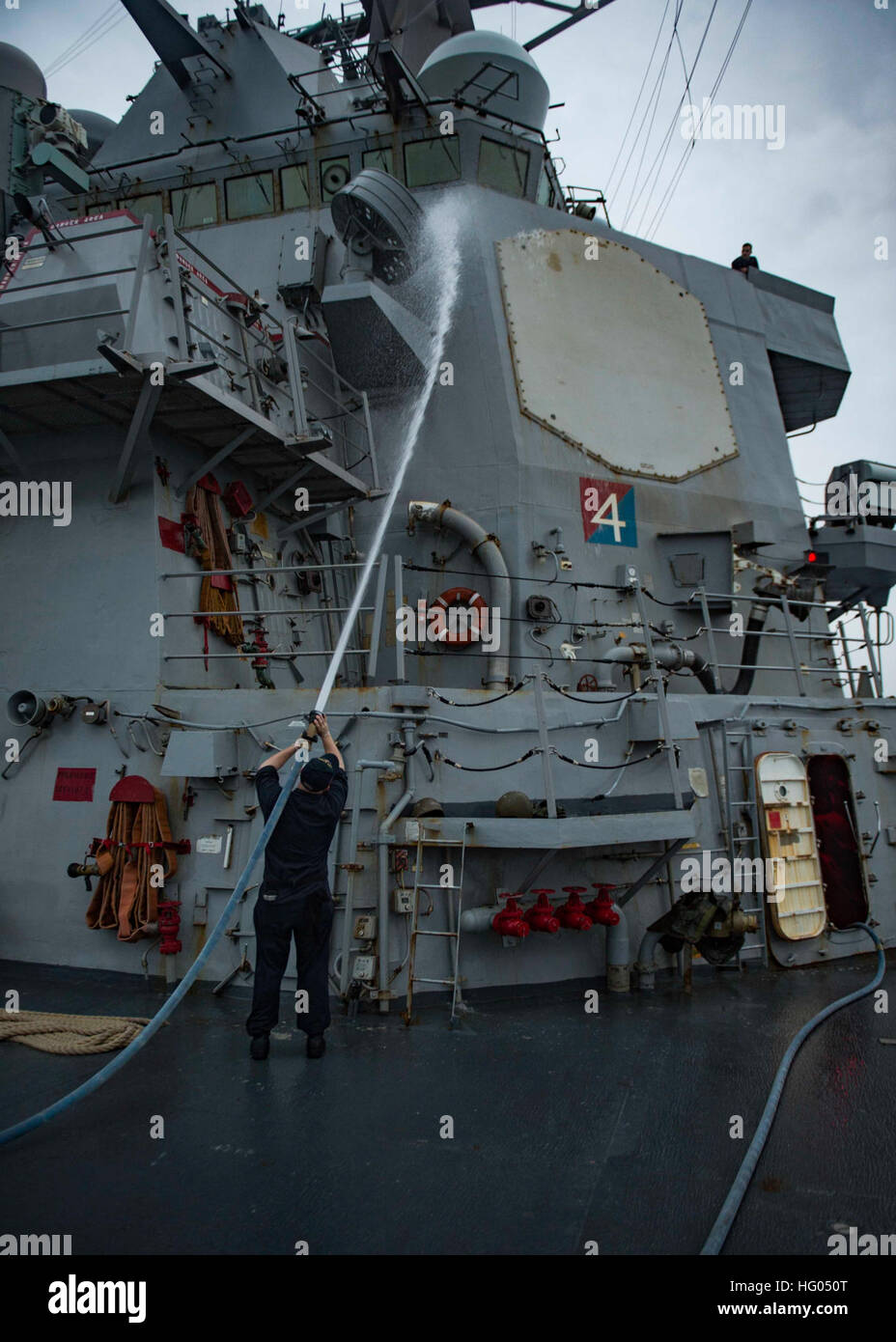 A petty officer sprays a bulkhead during a freshwater wash down aboard ...