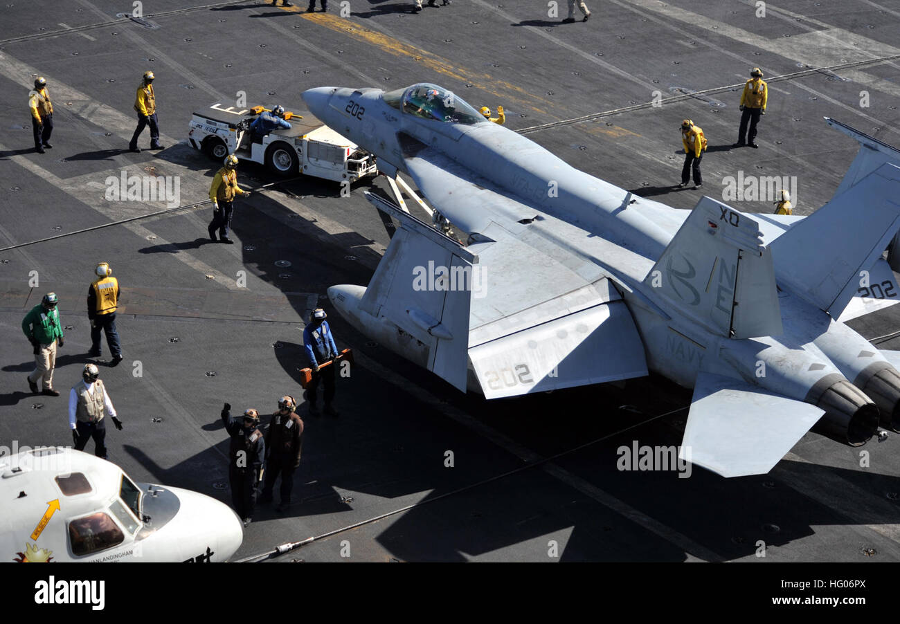 Sailors tow an F/A-18E Super Hornet from VFA-137 on the flight deck of ...