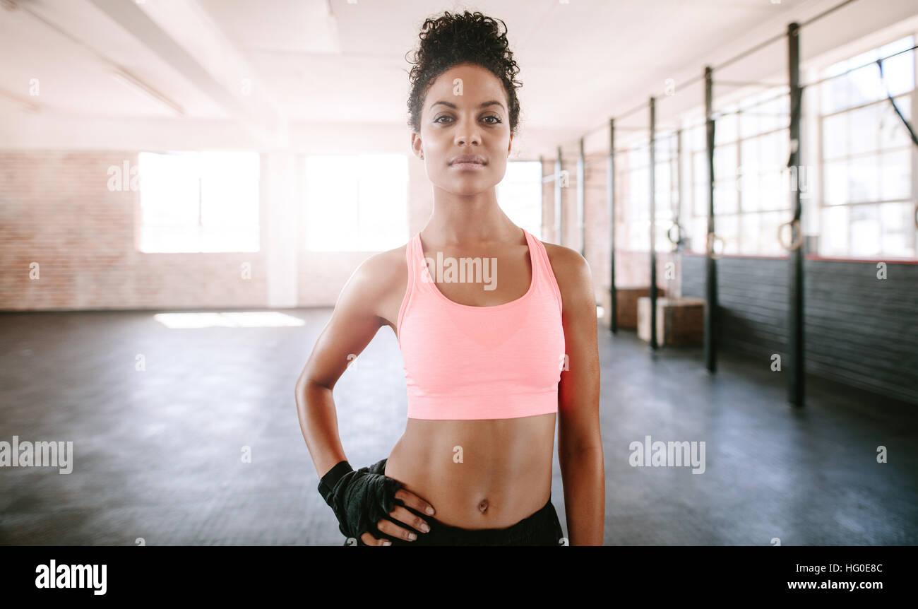 Portrait of confident young woman standing in gym. African female ...