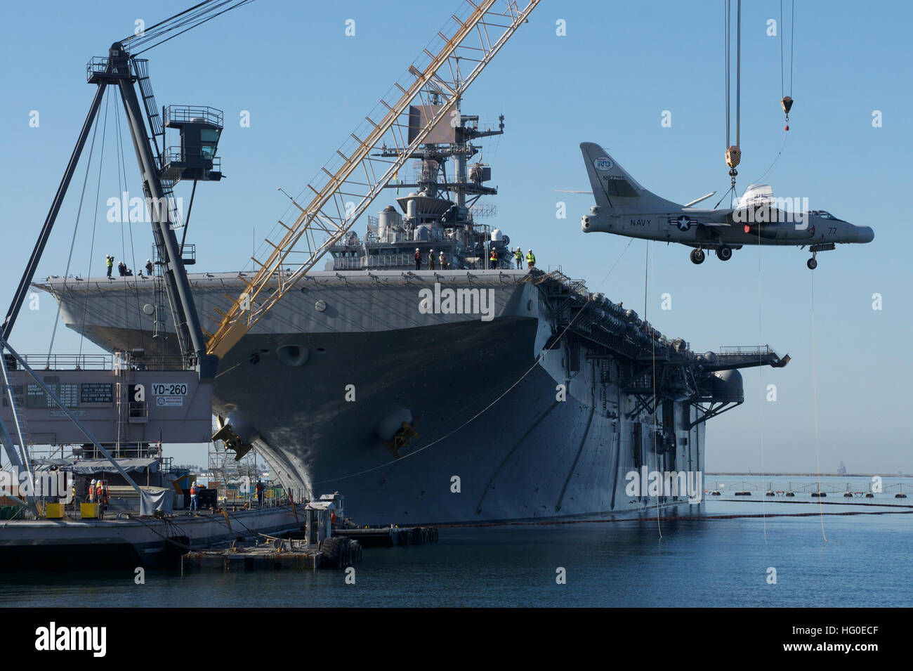 A Navy A3 aircraft is lifted by a barge crane to the flight deck of USS ...