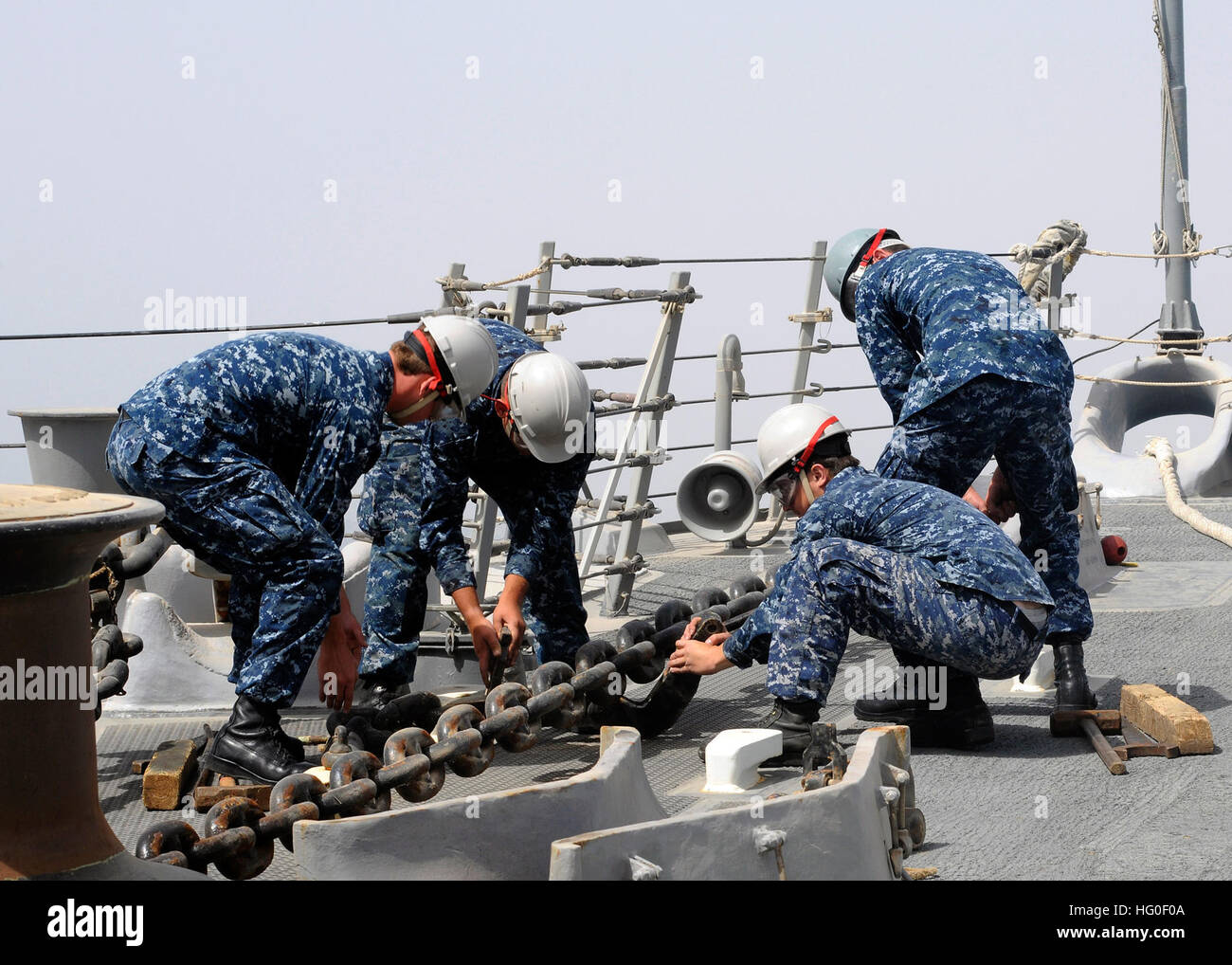 Sailors connect a pelican hook to the anchor chain of the Arleigh Burke ...