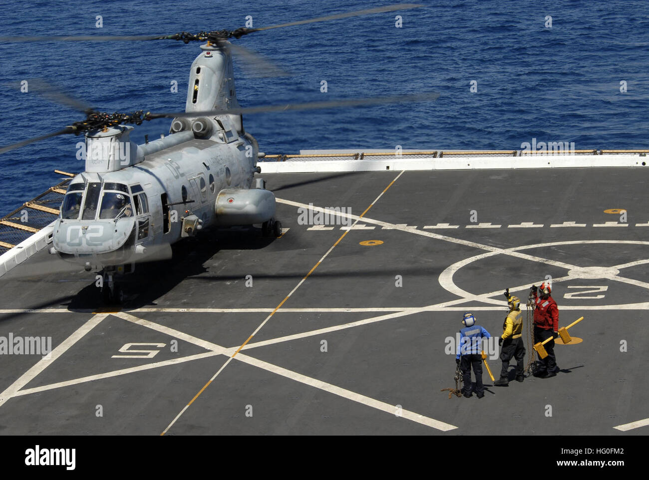 A plane captain signals a CH-46E Sea Knight helicopter assigned to the ...