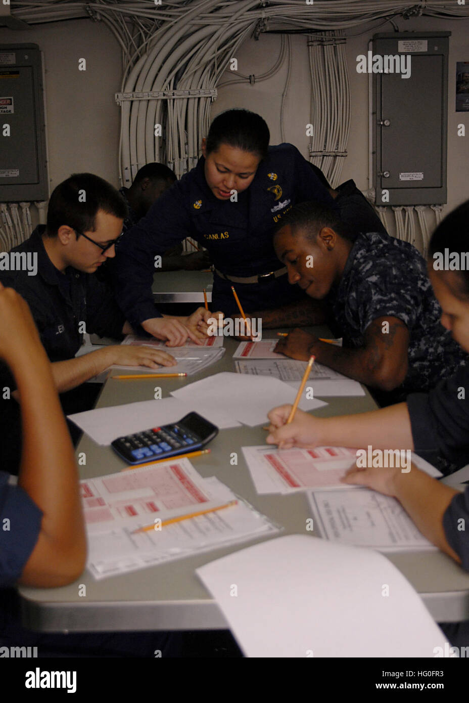 U.S. Navy Chief Navy Counselor Lalia Canlas, background, helps Sailors ...